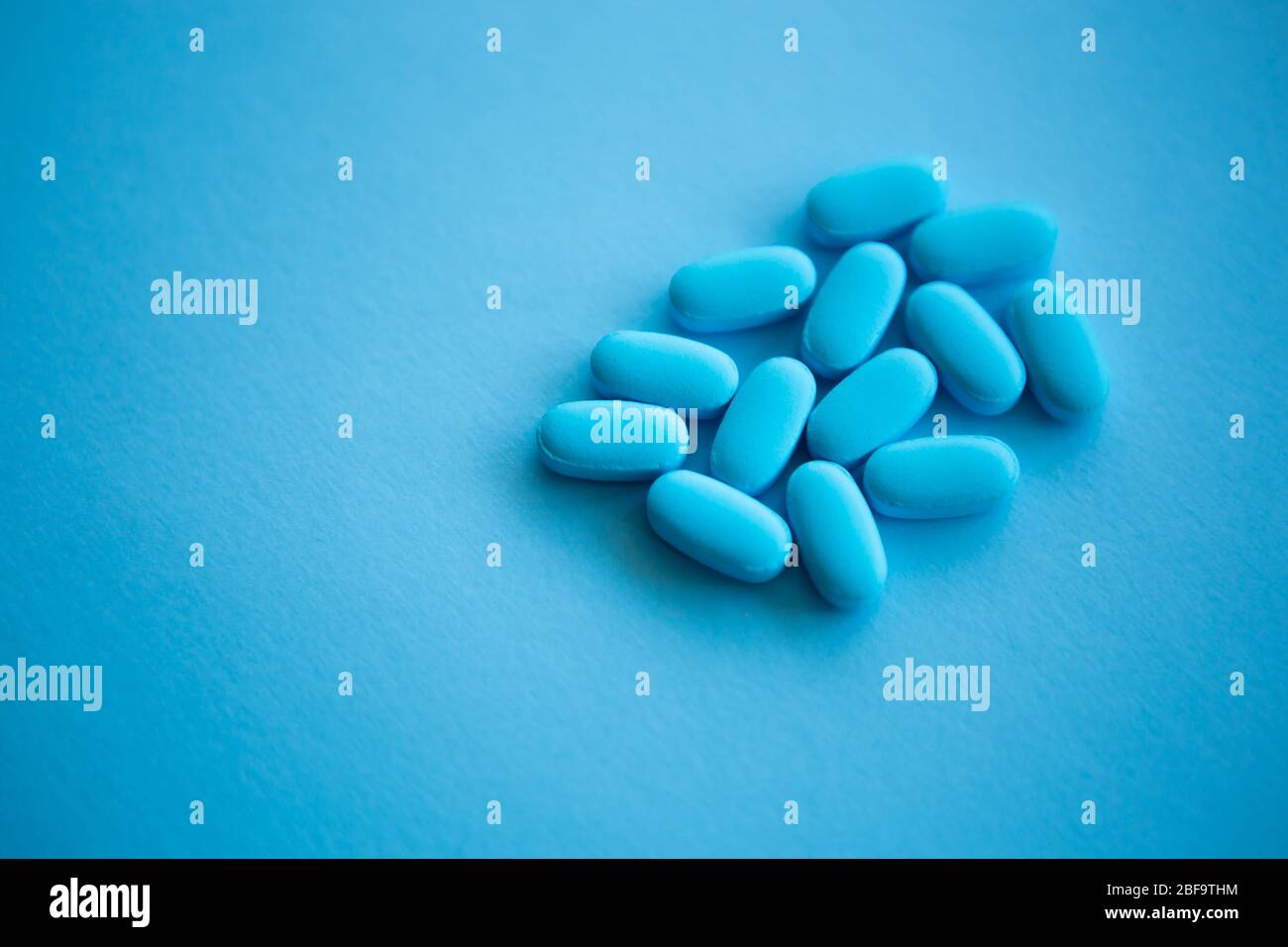 Blue medical pills in flat lay on empty backround.Vitamins drugs or ...
