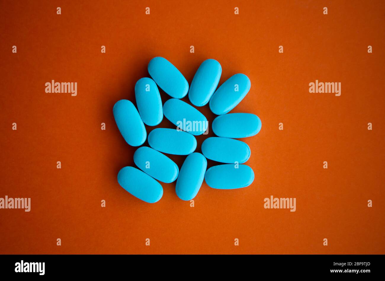 Blue medical pills in flat lay on empty orange backround.Vitamins drugs ...