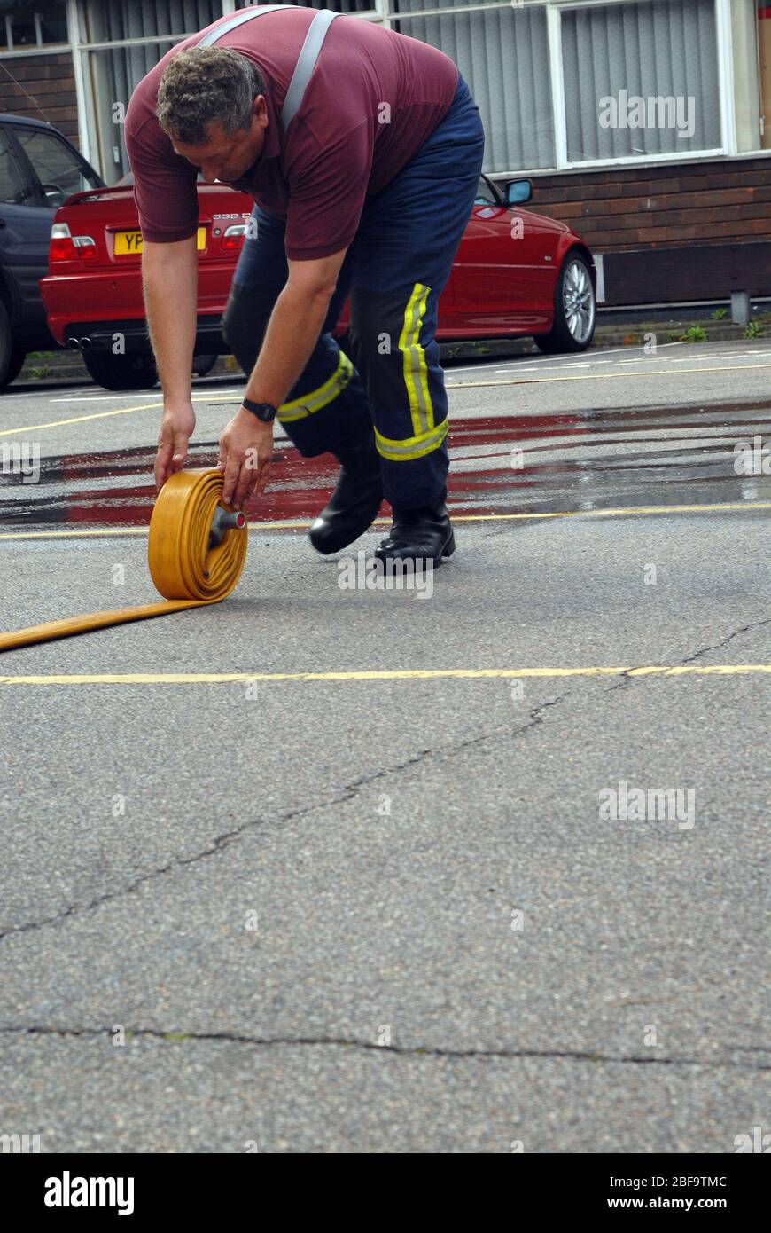 A fireman rolls up a fire hose Stock Photo - Alamy