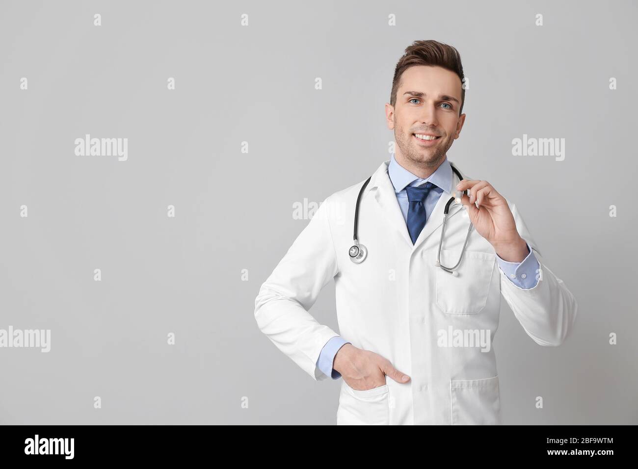 Male doctor with flashlight on grey background Stock Photo - Alamy