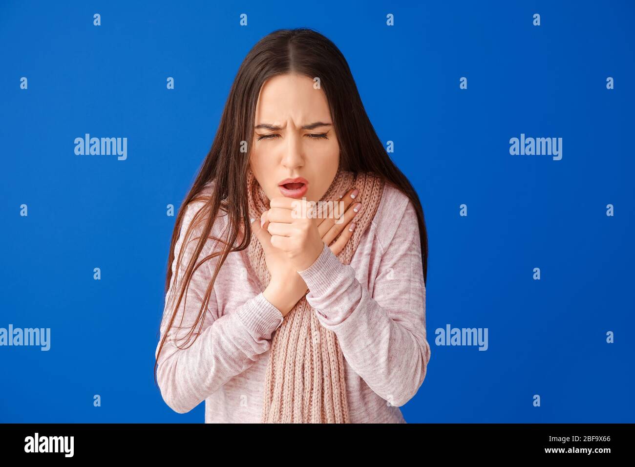Coughing young woman on color background Stock Photo - Alamy