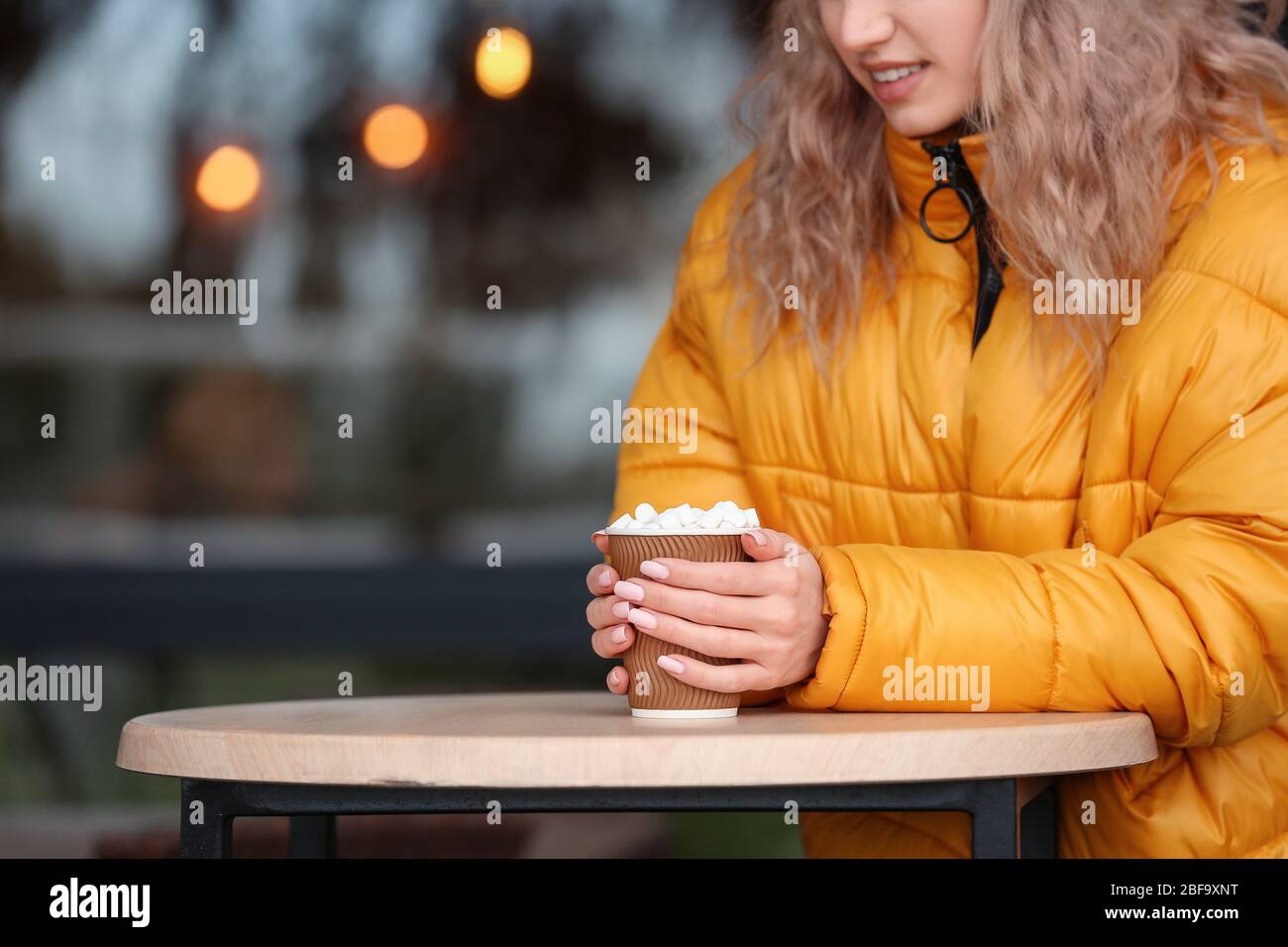 Beautiful young woman drinking hot cocoa in cafe outdoors Stock Photo ...
