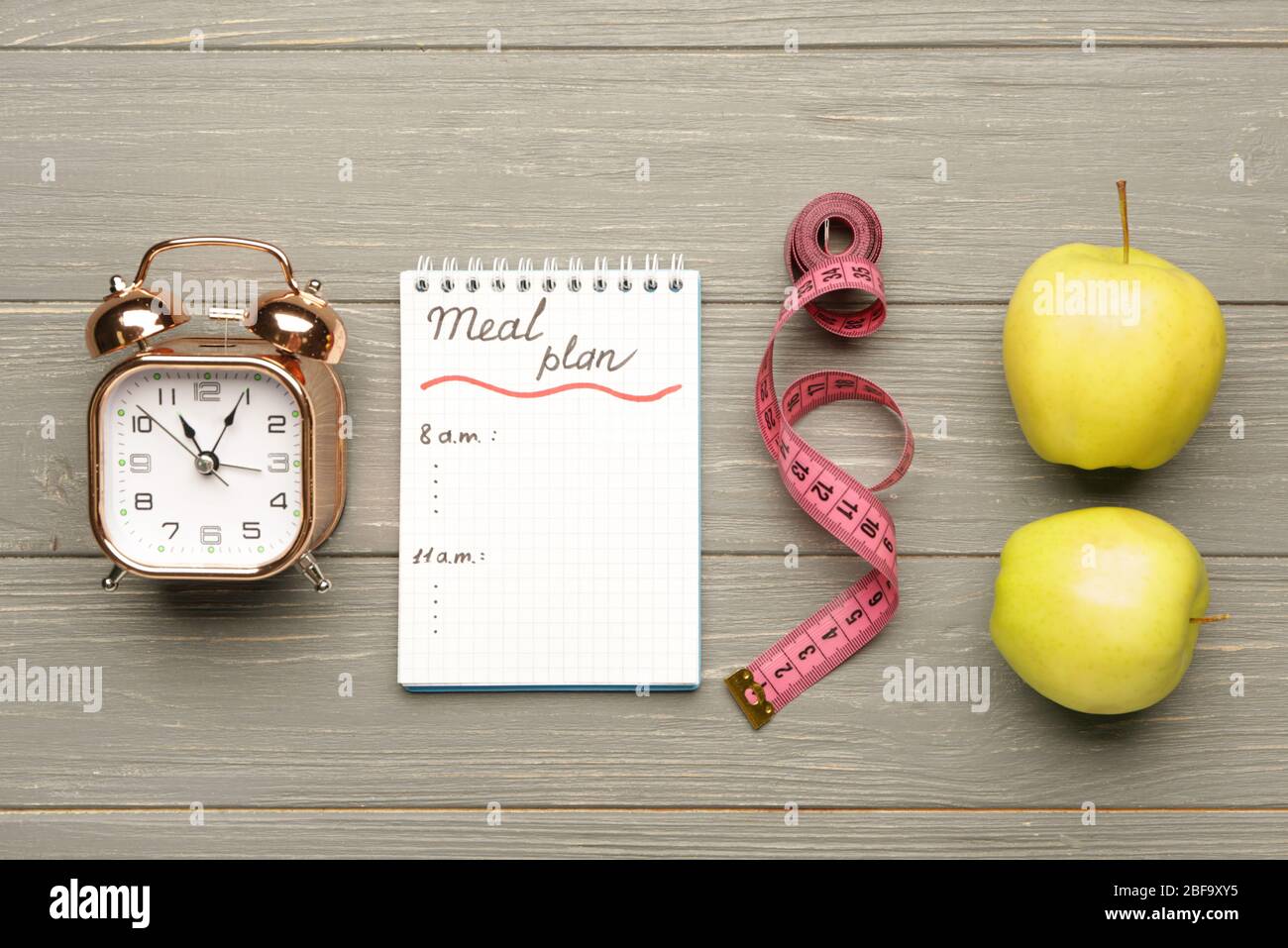 Meal plan with measuring tape, alarm clock and apples on table Stock ...