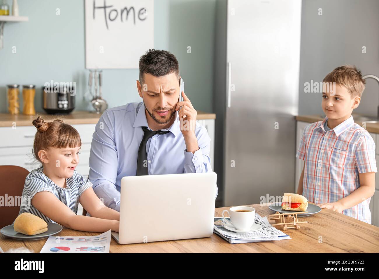 Little children keeping father from his work at home Stock Photo - Alamy