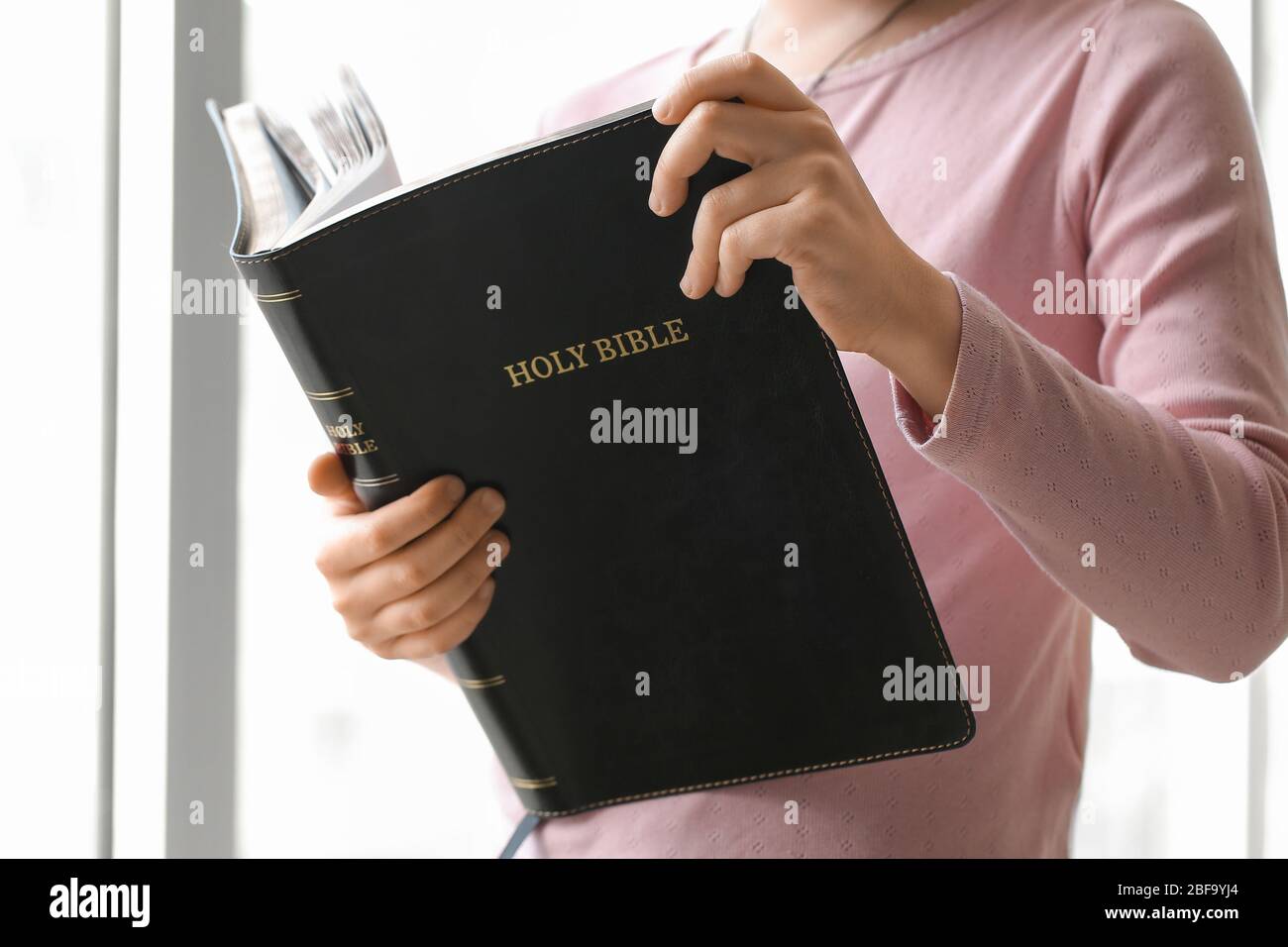 Cute little girl reading Bible at home Stock Photo - Alamy
