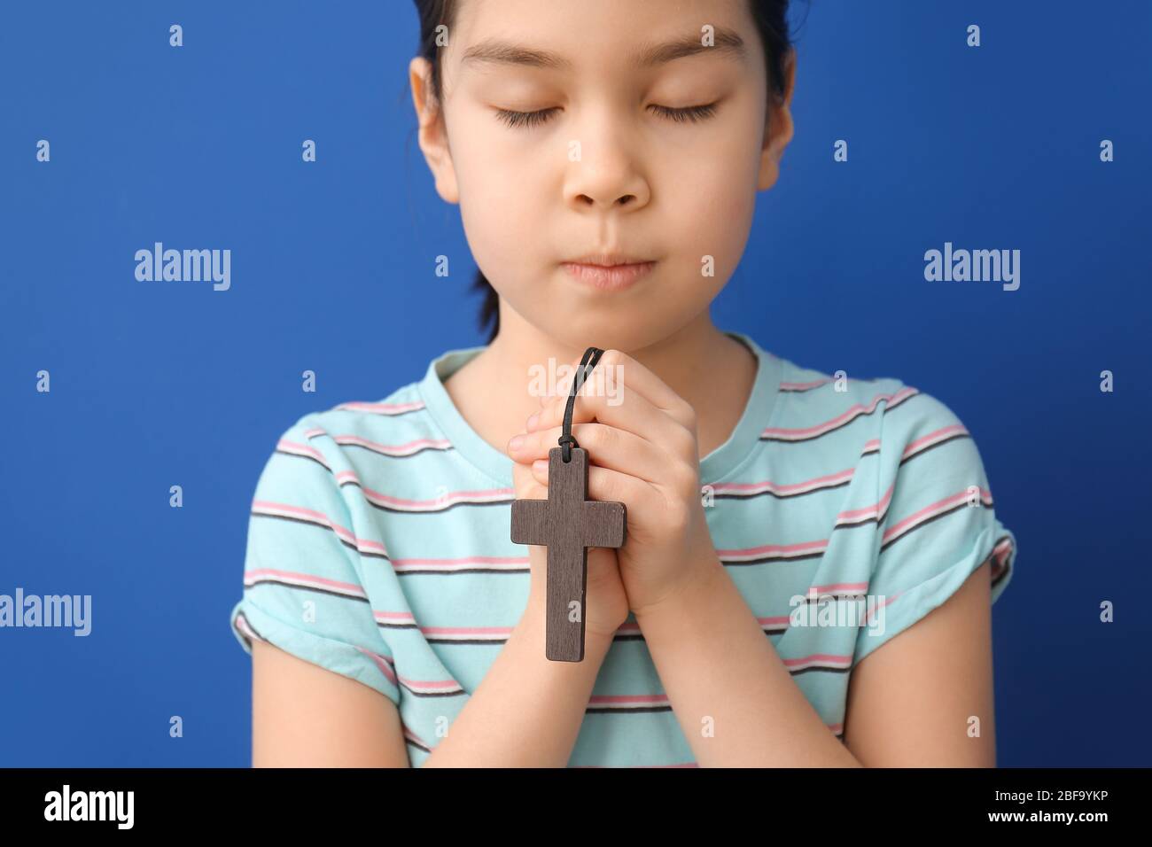Cute little Asian girl praying on color background Stock Photo - Alamy