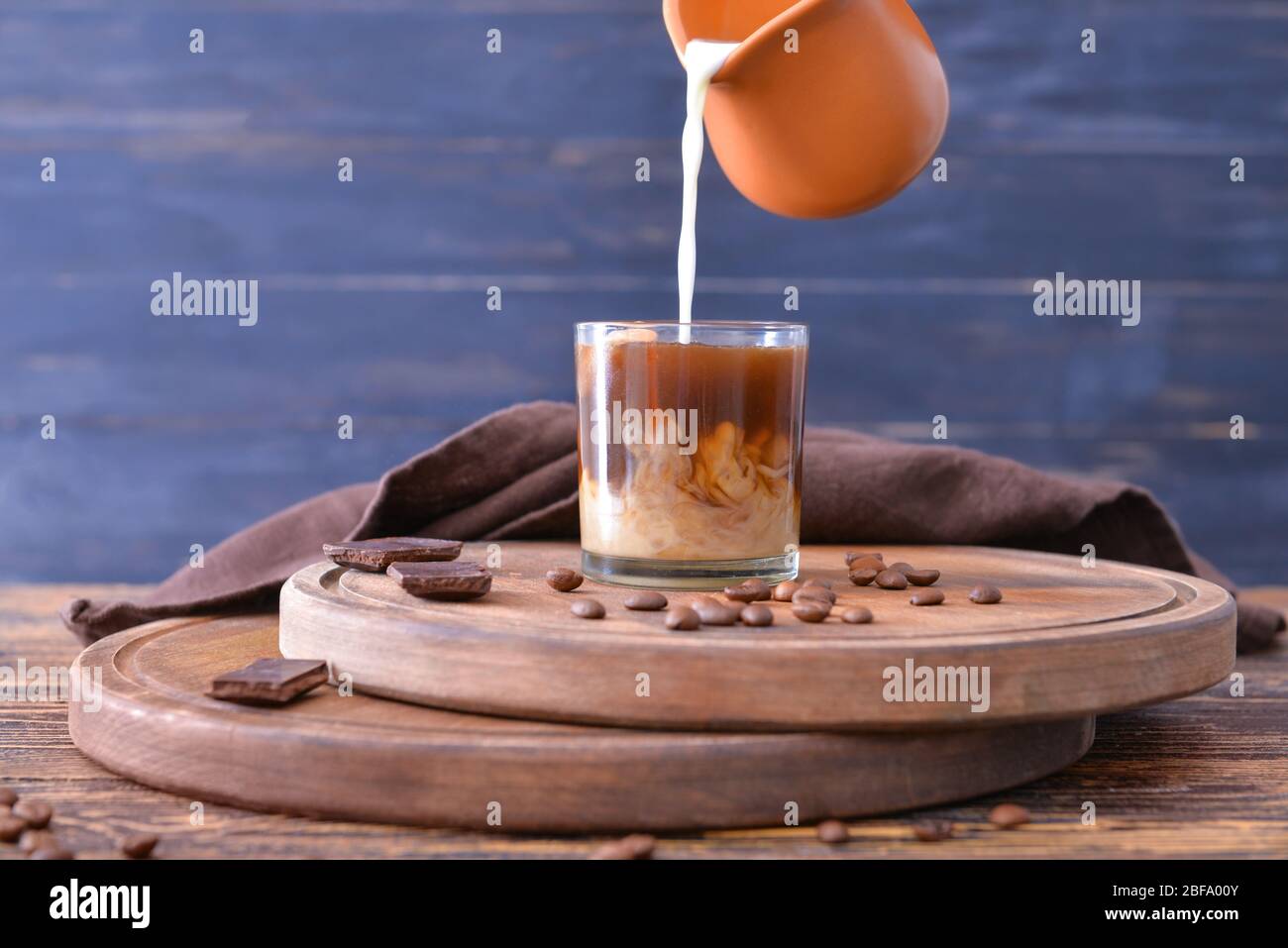 Pouring of milk into cold coffee in glass on table Stock Photo - Alamy