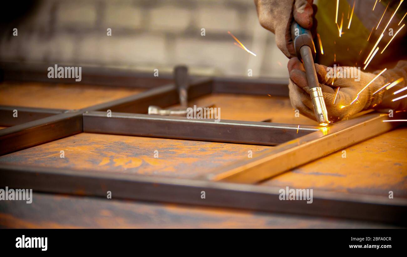 Grinding the seams of metal frame in the workshop. Mid shot Stock Photo ...