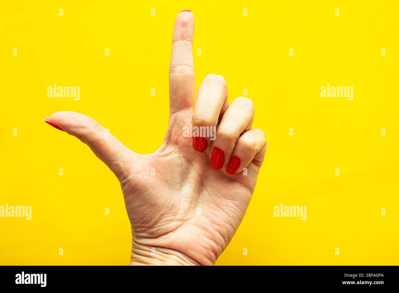 Woman's hand shows the point gesture over bright yellow background ...
