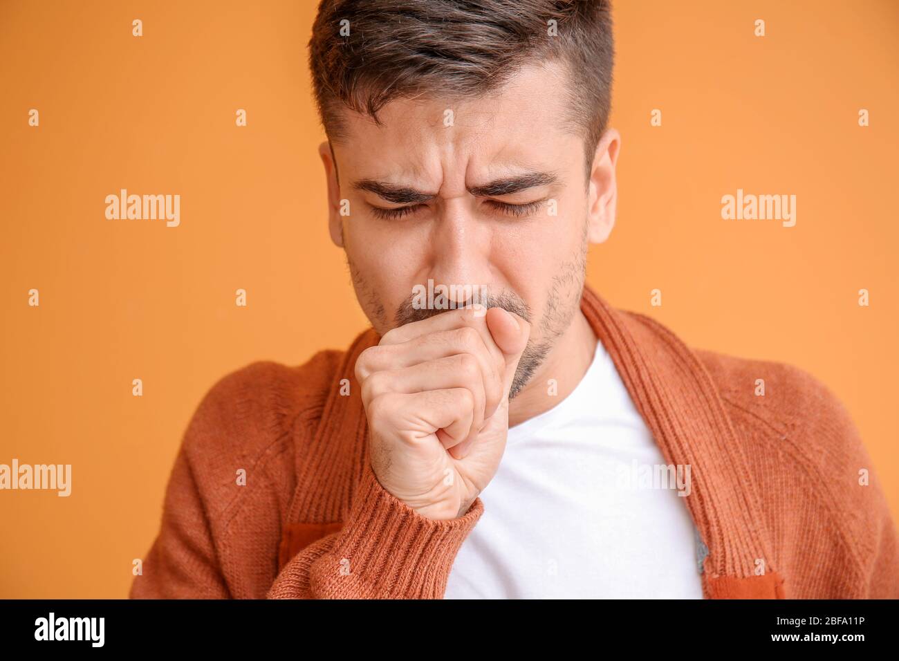 Coughing young man on color background Stock Photo - Alamy
