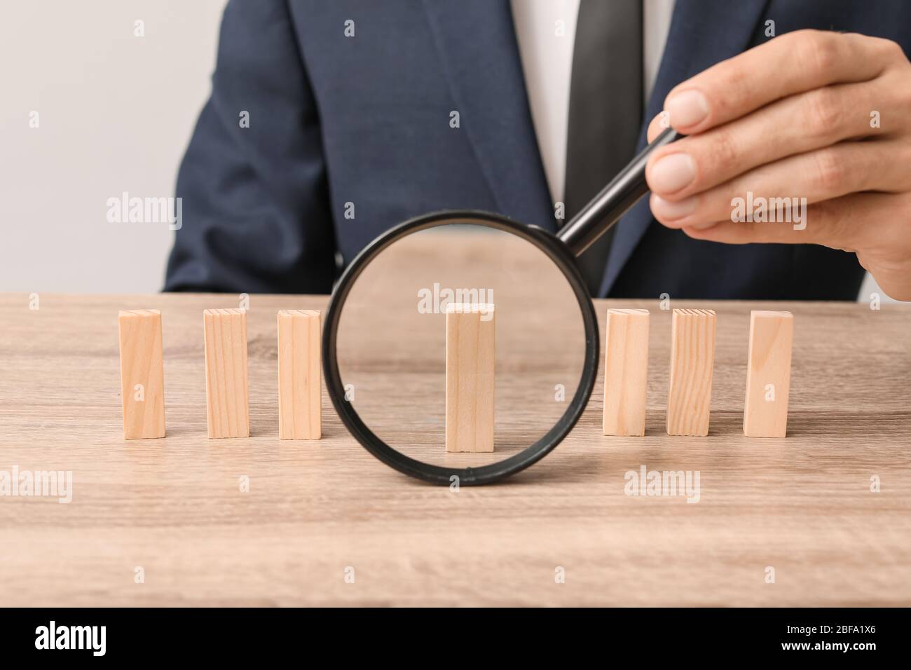 Man looking at wooden blocks on table through magnifier. Concept of ...