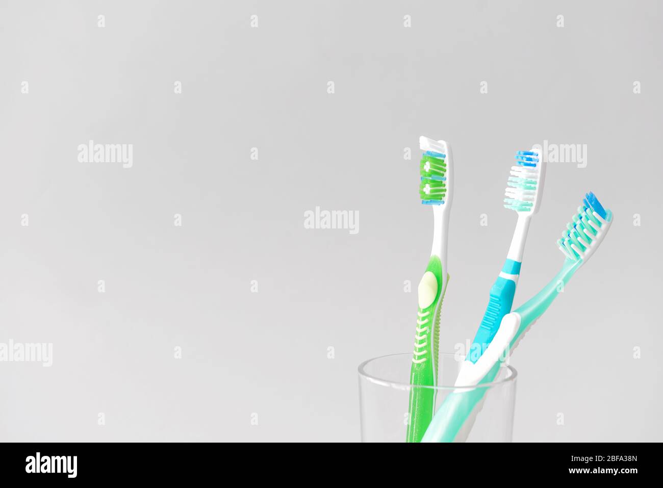 Tooth brushes in glass on light background Stock Photo - Alamy