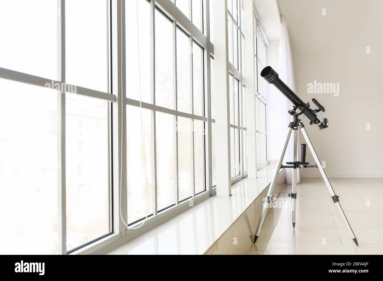 Modern telescope near window in room Stock Photo - Alamy