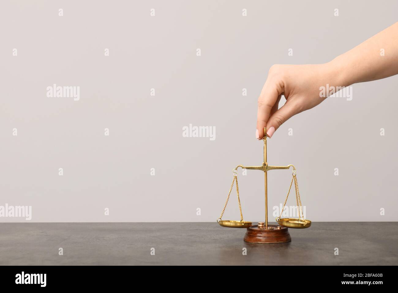 Female hand putting scales of justice on table Stock Photo - Alamy