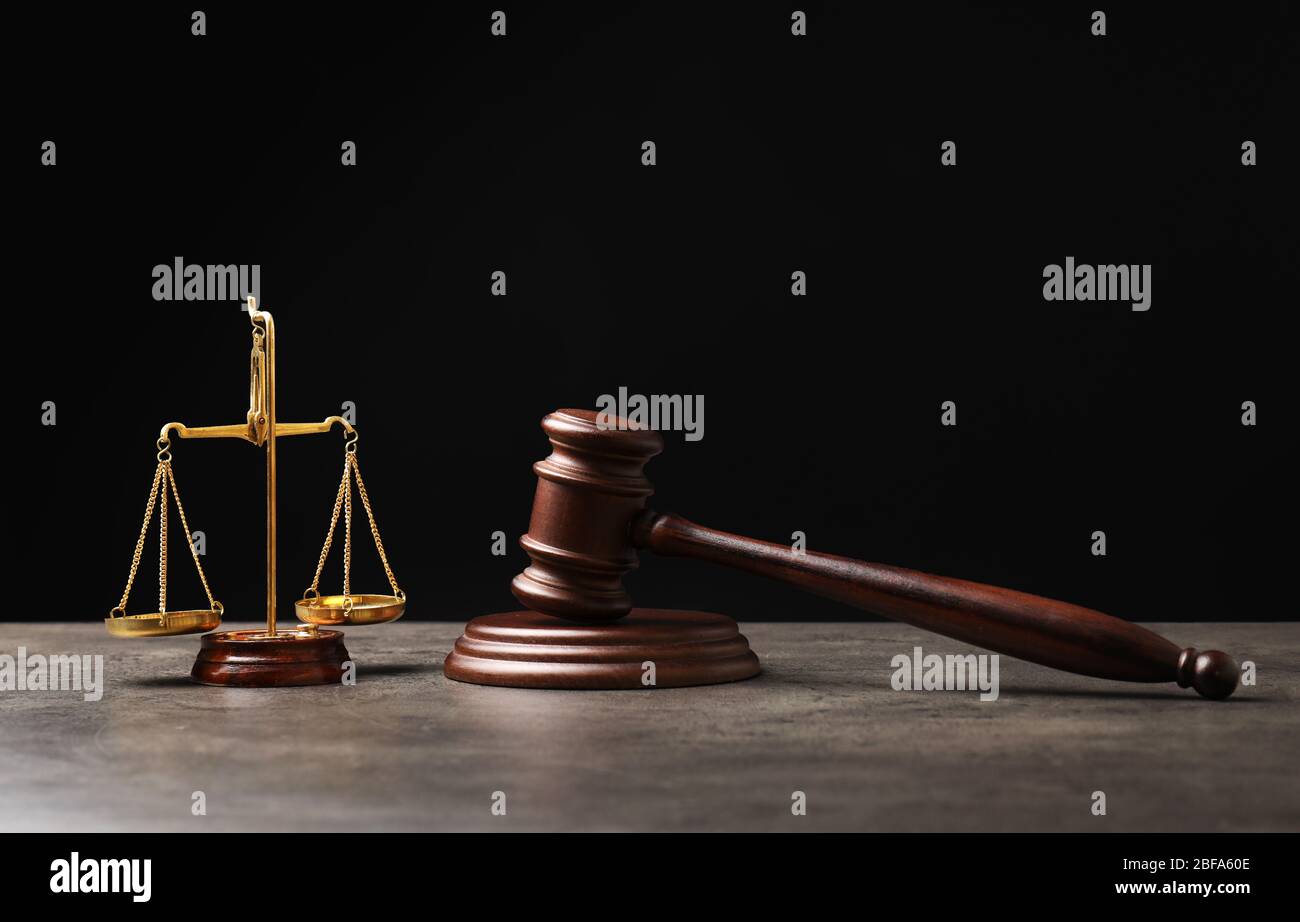 Judge's gavel and scales of justice on table against dark background ...