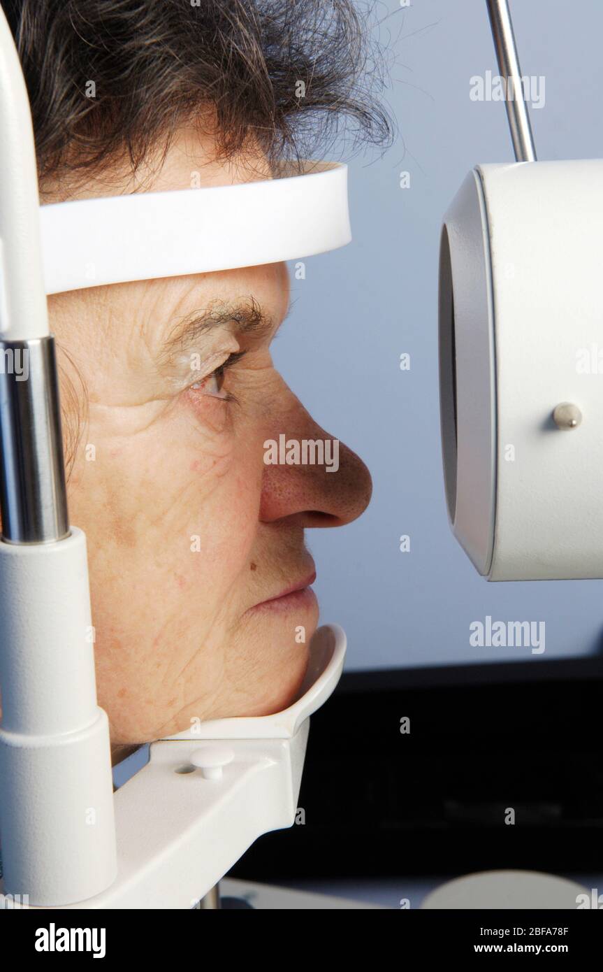 An optometrist examines a patient’s eye with a slit lamp. The ...