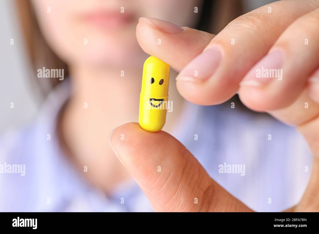Woman holding pill with drawn happy face, closeup Stock Photo - Alamy