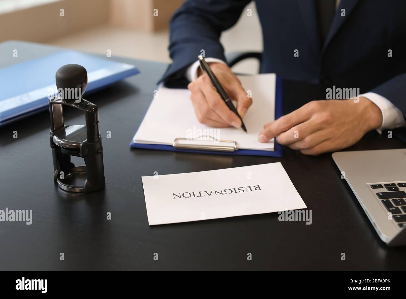 Paper with text RESIGNATION on table of office worker Stock Photo - Alamy