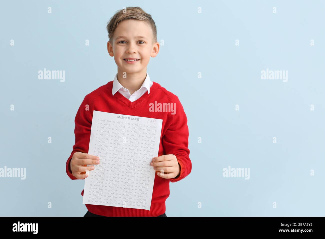Pupil with answer sheet for school test on color background Stock Photo ...