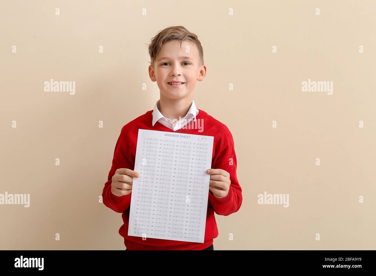 Pupil with answer sheet for school test on color background Stock Photo ...