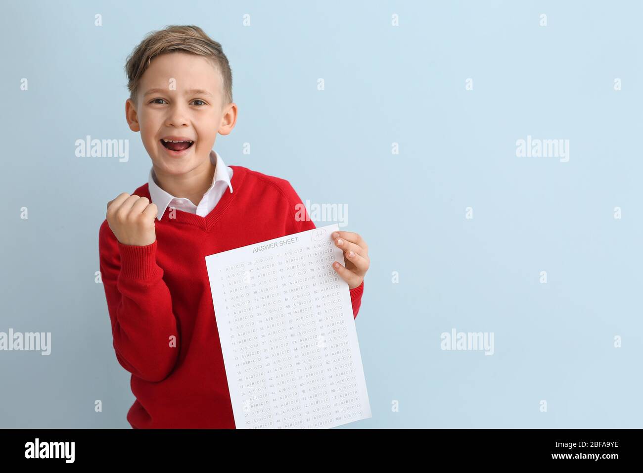 Pupil with answer sheet for school test on color background Stock Photo ...