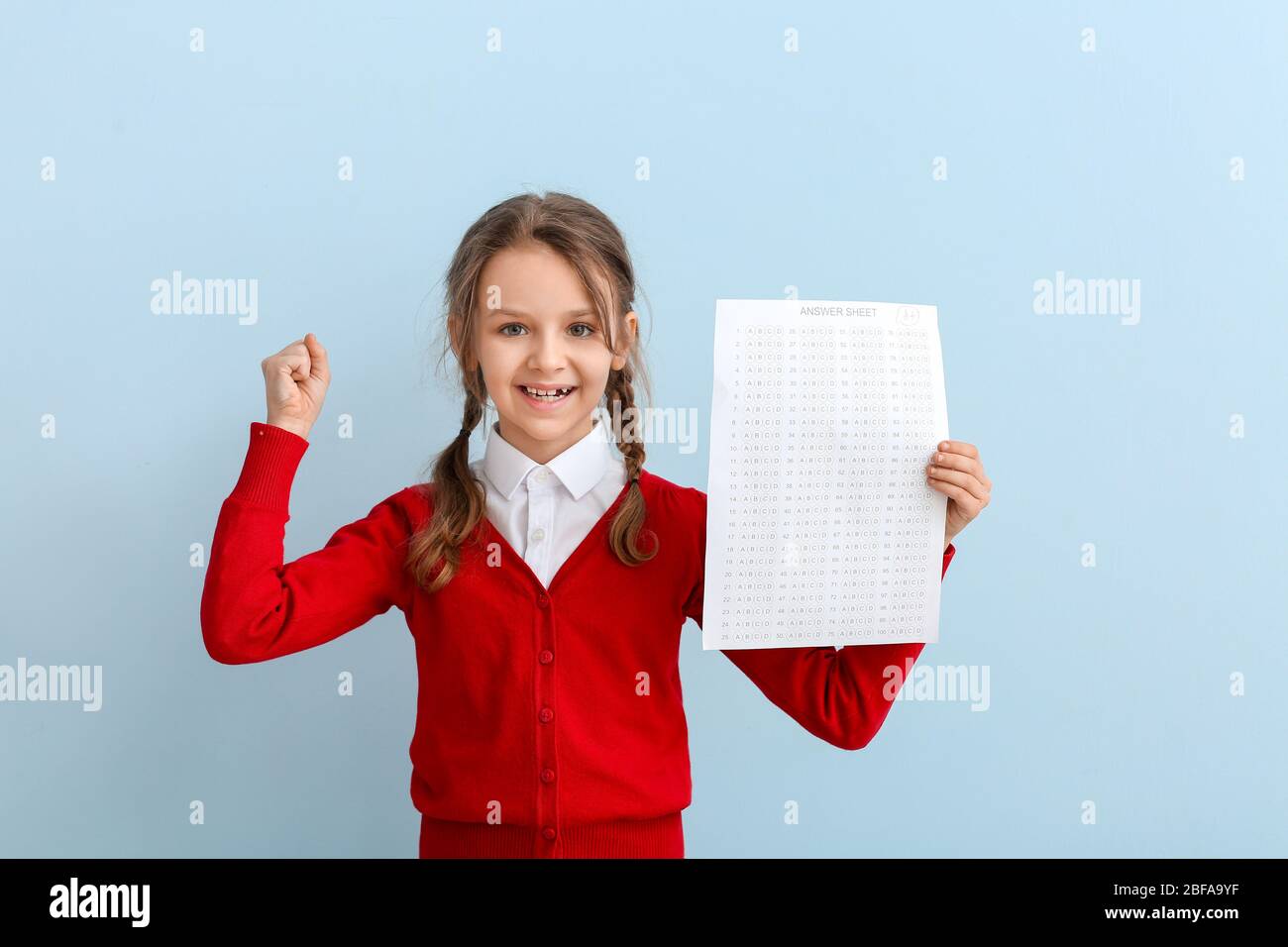 Pupil with answer sheet for school test on color background Stock Photo ...