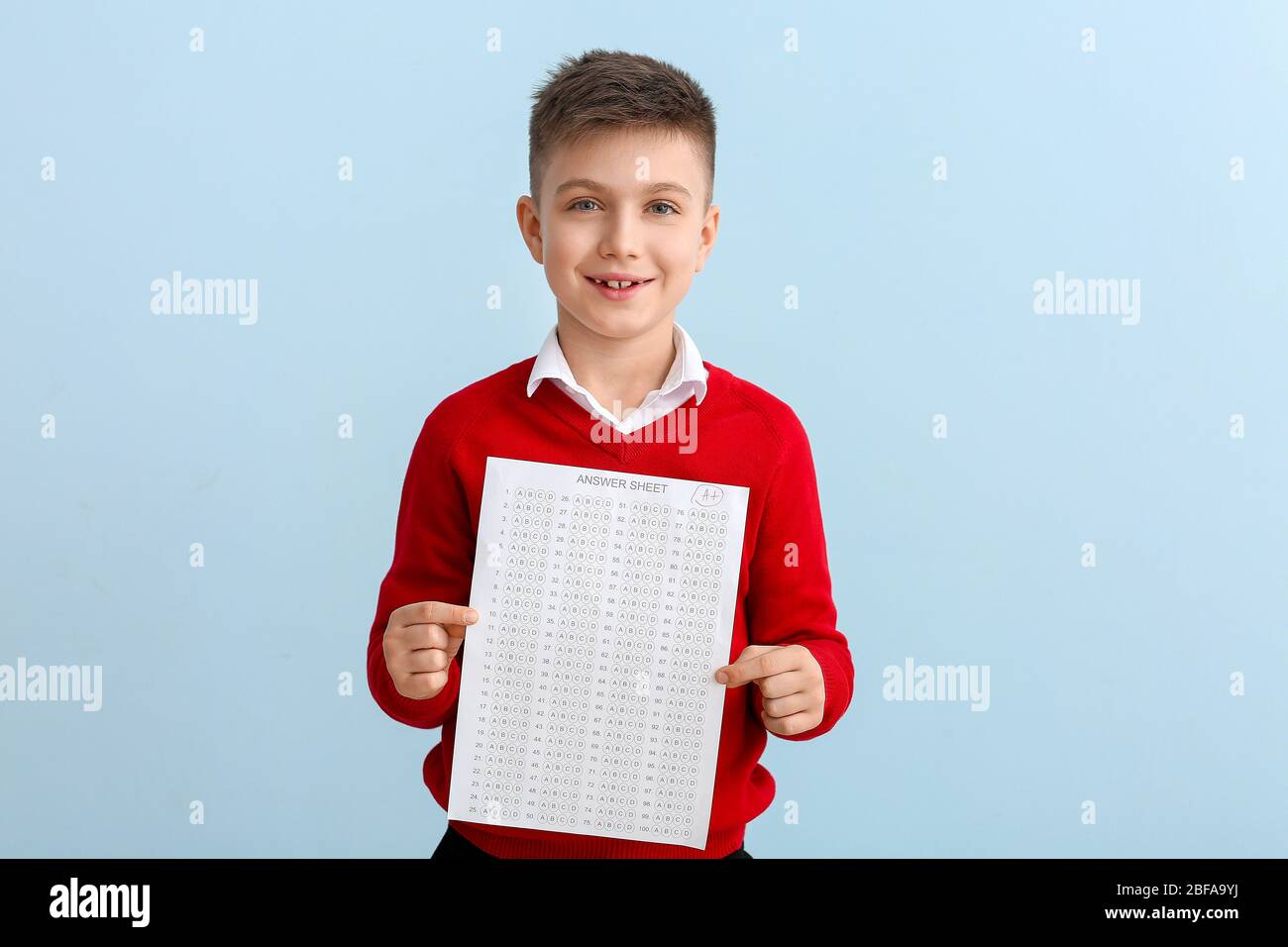 Pupil with answer sheet for school test on color background Stock Photo ...