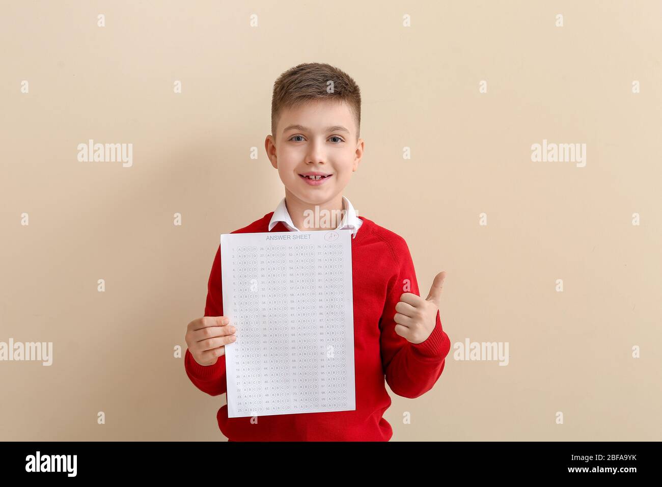 Pupil with answer sheet for school test on color background Stock Photo ...