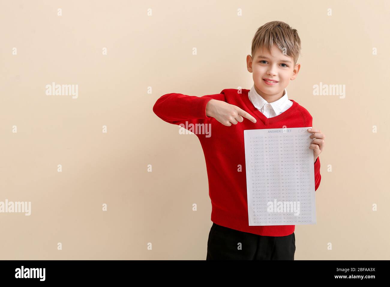 Pupil with answer sheet for school test on color background Stock Photo ...
