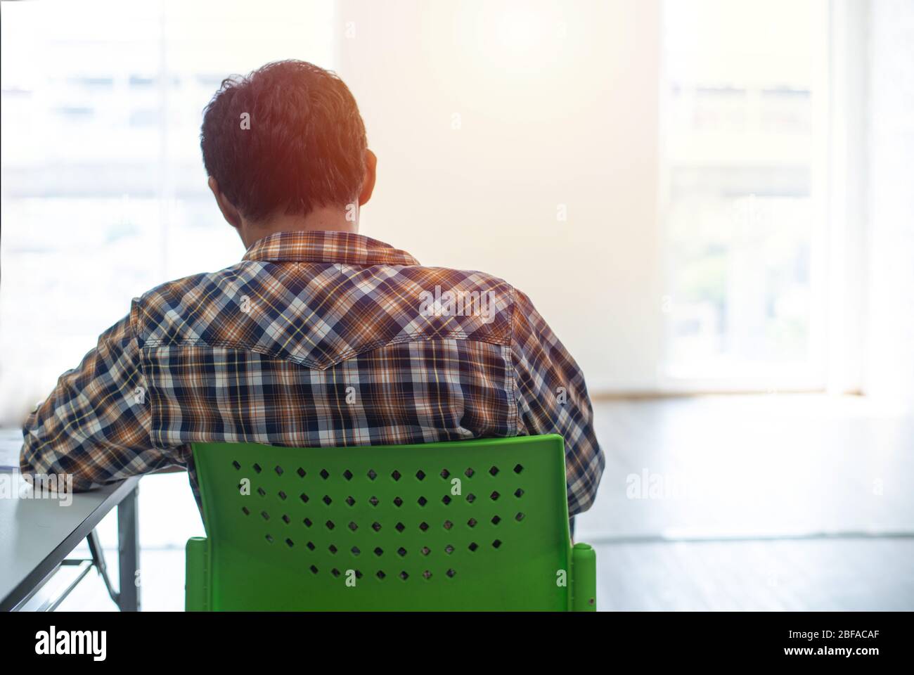 the backside of Asian man sitting one person on chair lean table in the ...