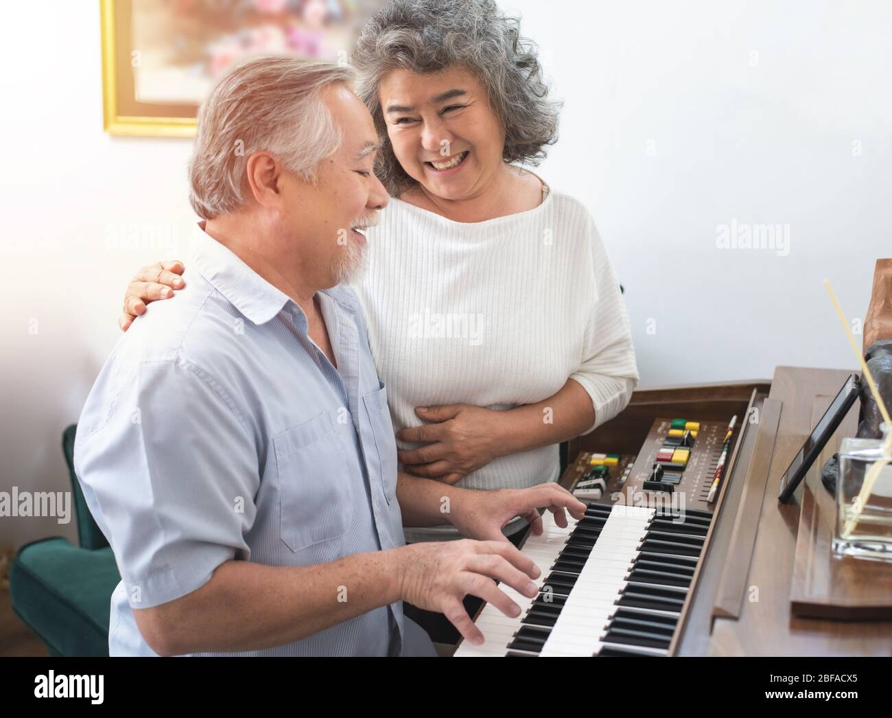 Senior elderly man plays piano in nursing home listened to by elderly ...