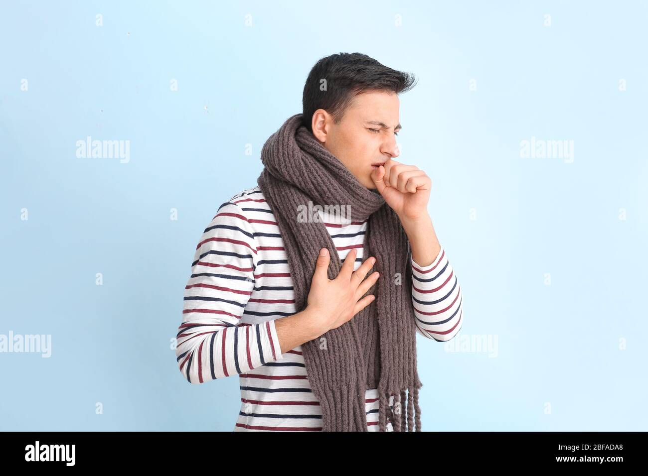 Coughing young man on light background Stock Photo - Alamy