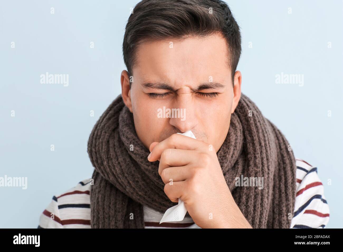 Coughing young man on light background Stock Photo - Alamy