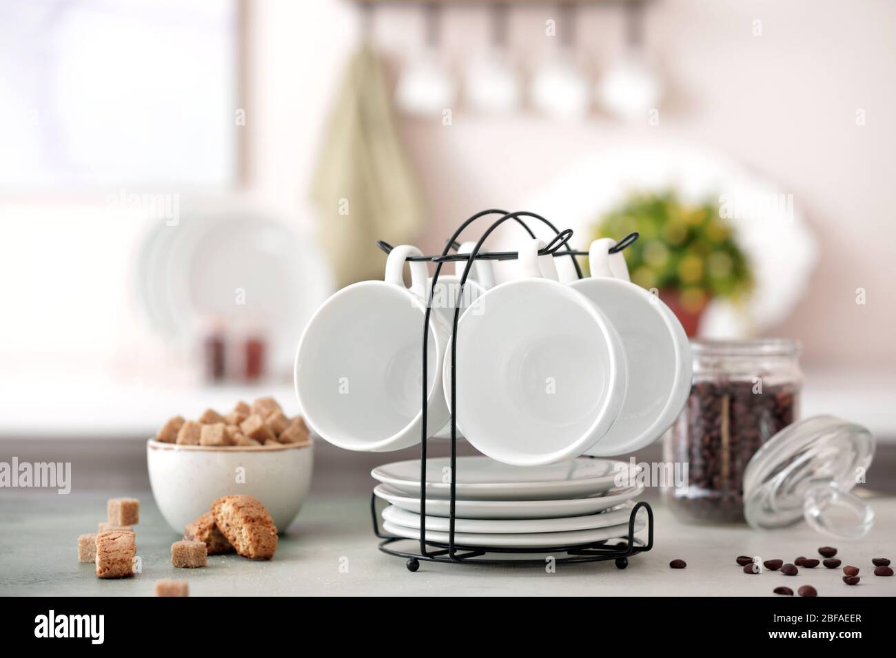 Holder with cups and saucers on kitchen table Stock Photo - Alamy