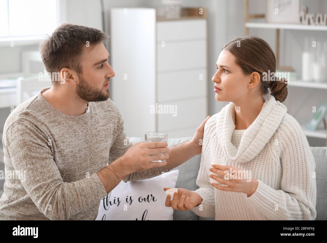 Man giving water to his wife who is going to take medicine at home ...