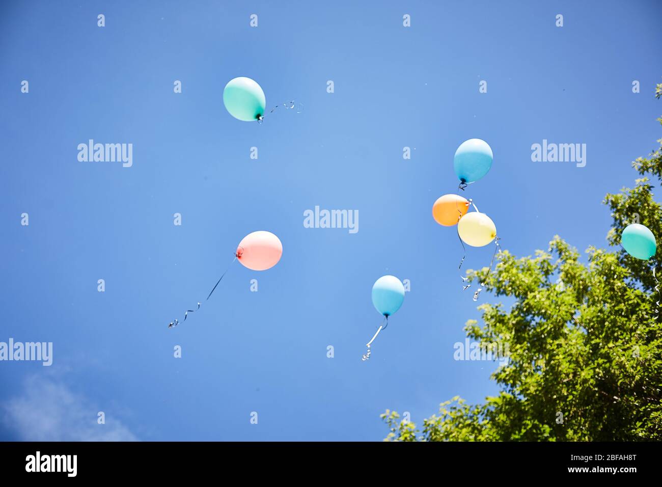 balloons fly away on a background of blue sky Stock Photo - Alamy