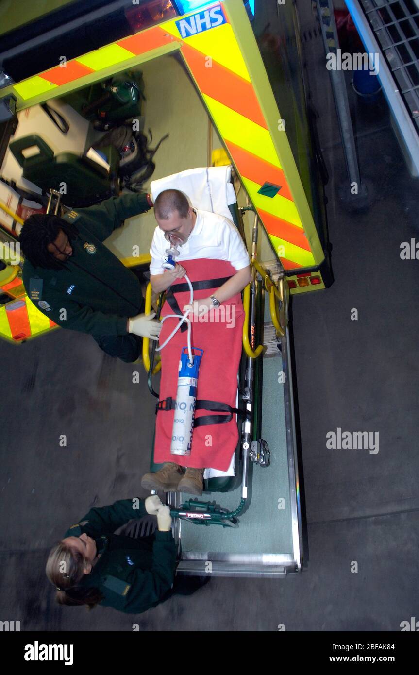 Paramedicas load a patient into the back of an ambulance. The patient ...