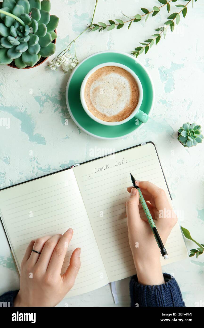 Cup of coffee on table of woman writing in notebook Stock Photo - Alamy
