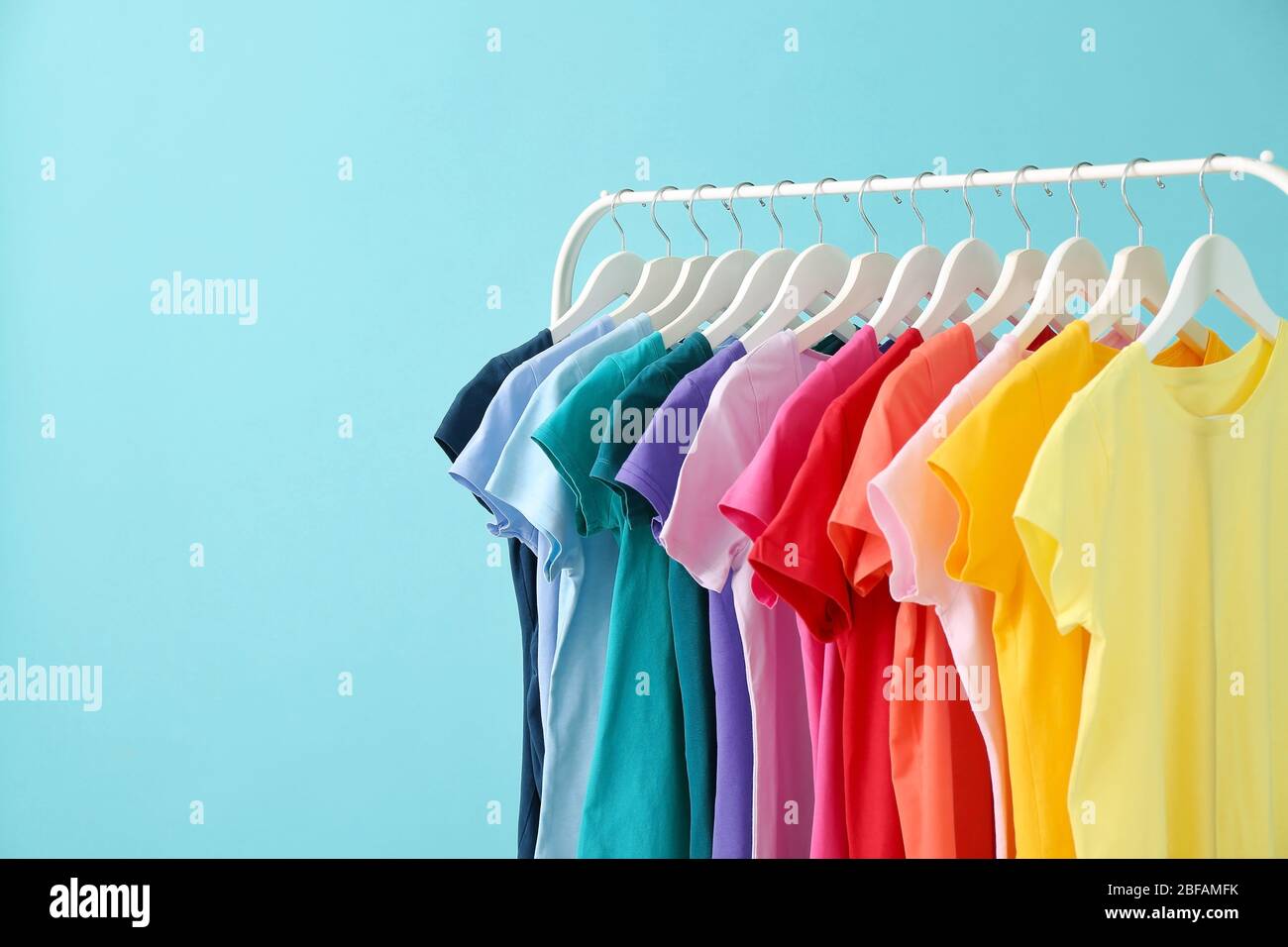 Rack with hanging clothes on color background Stock Photo - Alamy