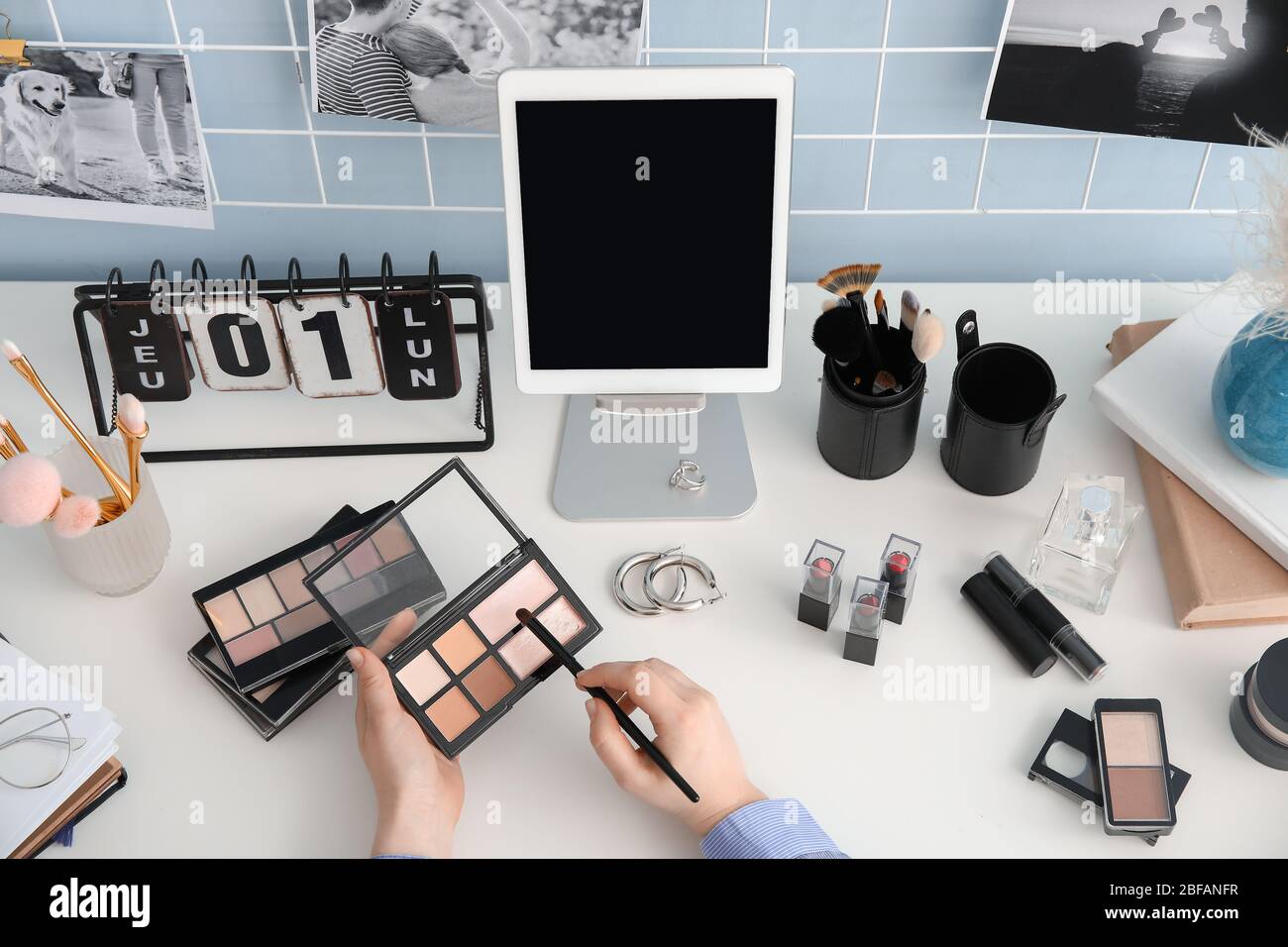 Makeup artist at table with modern tablet computer and cosmetics Stock ...