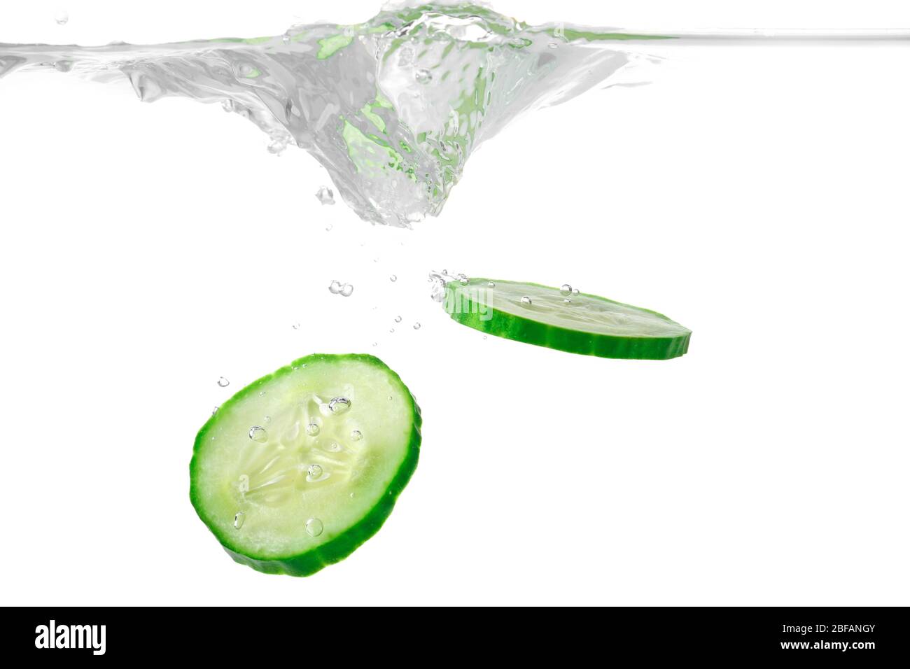 Falling of fresh cucumber slices into water against white background Stock Photo - Alamy