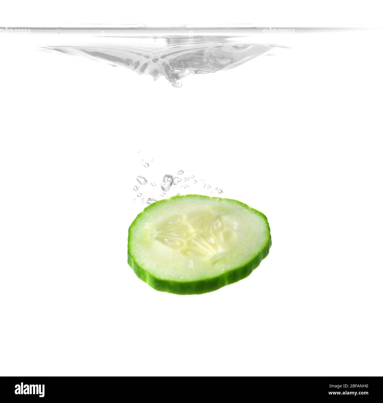 Falling of fresh cucumber slice into water against white background ...