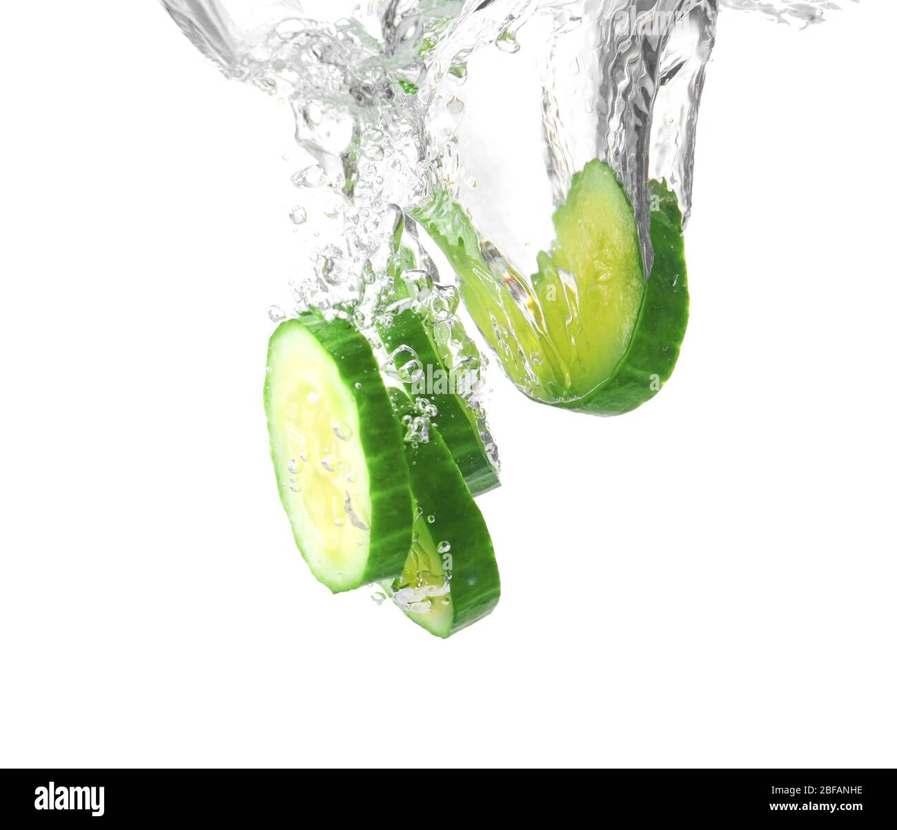 Falling of fresh cucumber slices into water against white background Stock Photo - Alamy