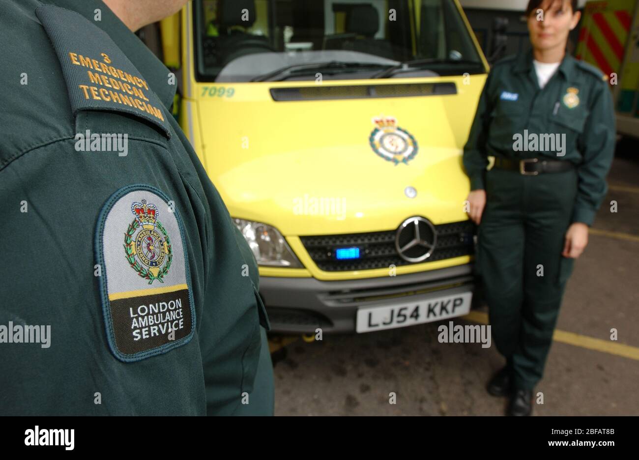 An ambulance technician and paramedic wait in front of an ambulance ...