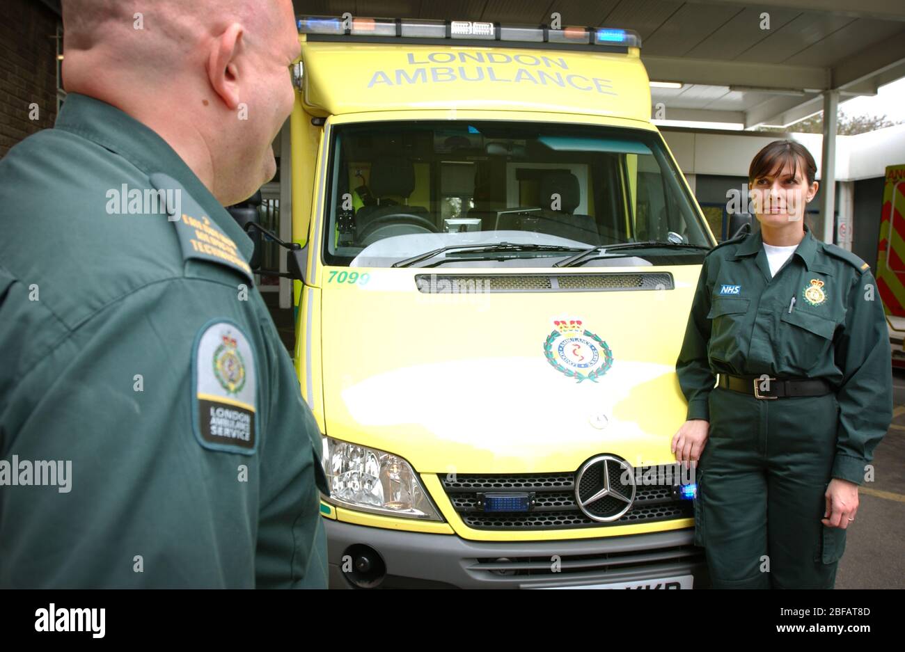An ambulance technician and paramedic wait in front of an ambulance ...