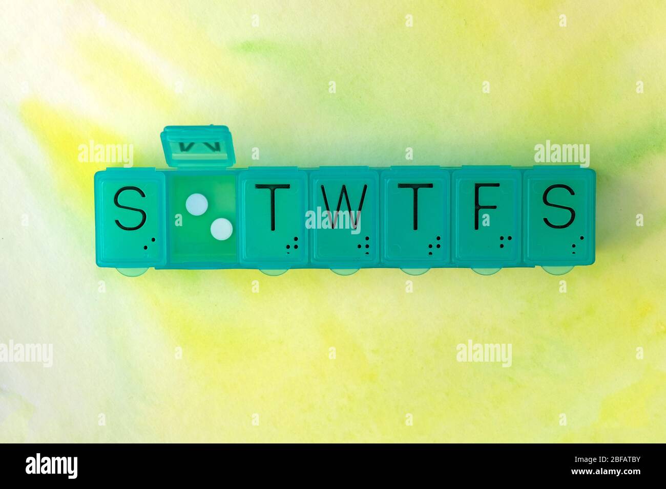 Green plastic pill box for seven days on a yellow background. Pill ...