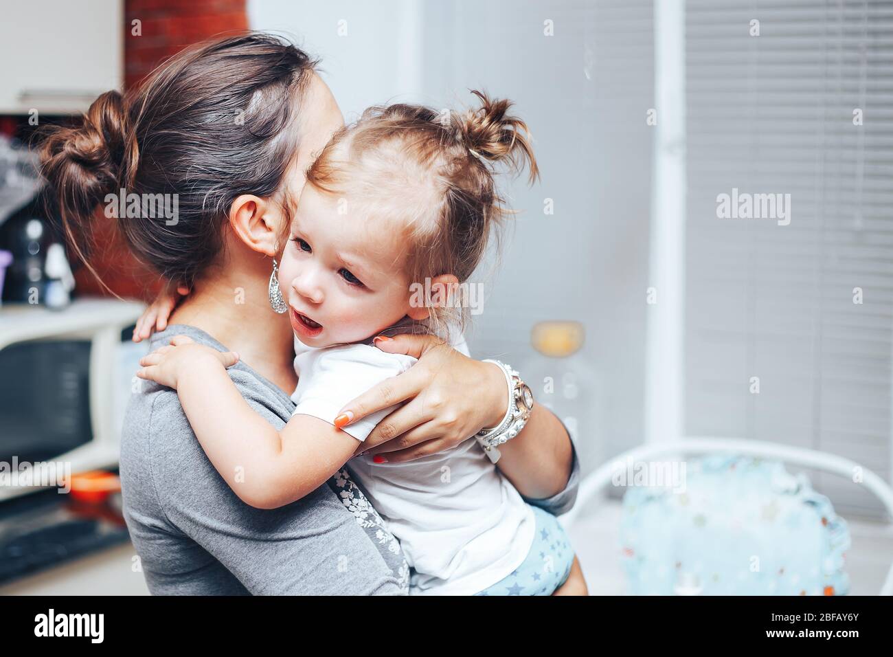 crying girl on mother hands at home with dark hair, mother hugging her ...