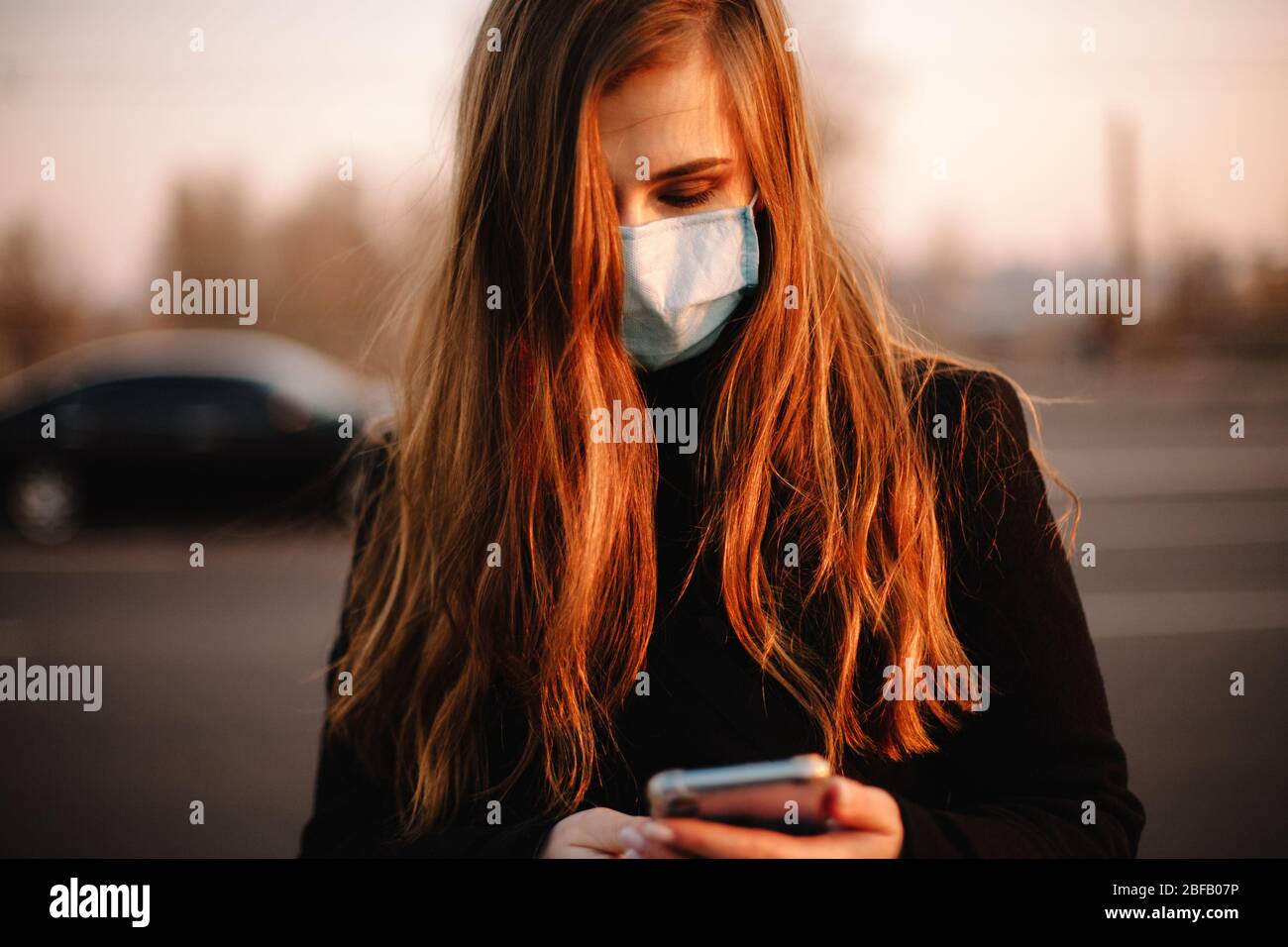 Portrait of young woman wearing protective face medical mask using ...