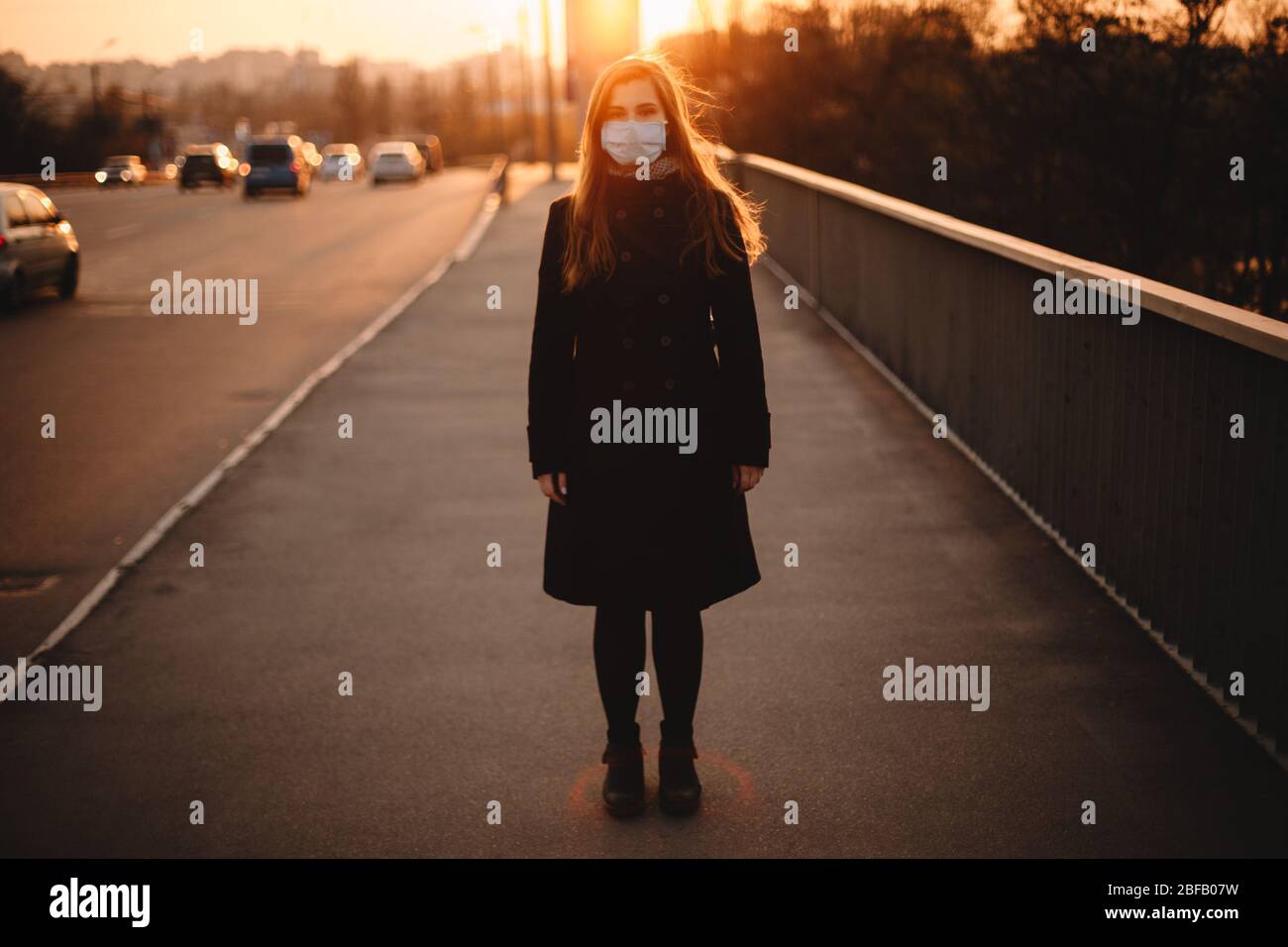 Portrait of young woman wearing protective face medical mask while ...