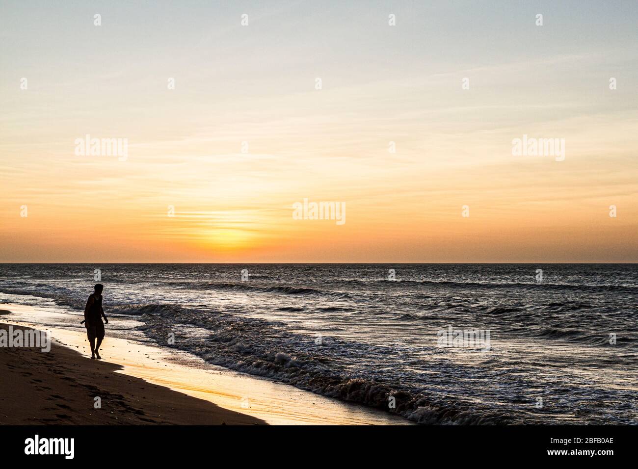 Silhouette of a man walking on Medanos Blancos Beach at sunset, in ...